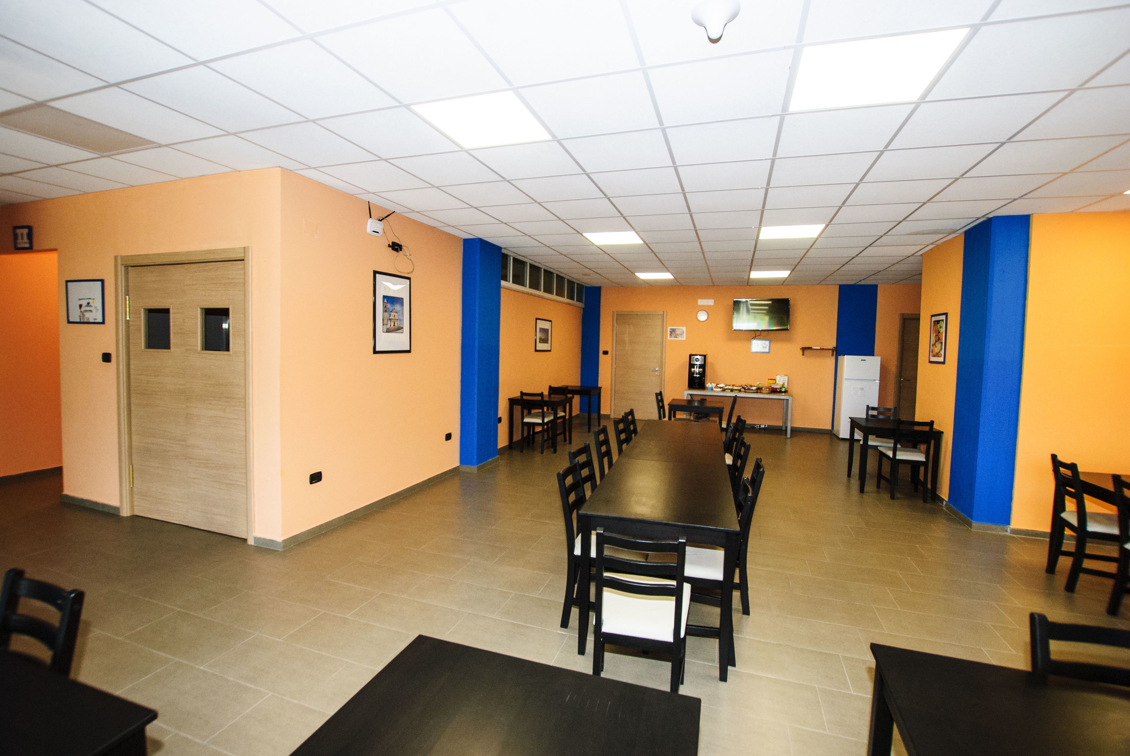 Uma sala de conferências com uma mesa comprida e cadeiras, uma porta e uma pequena copa.