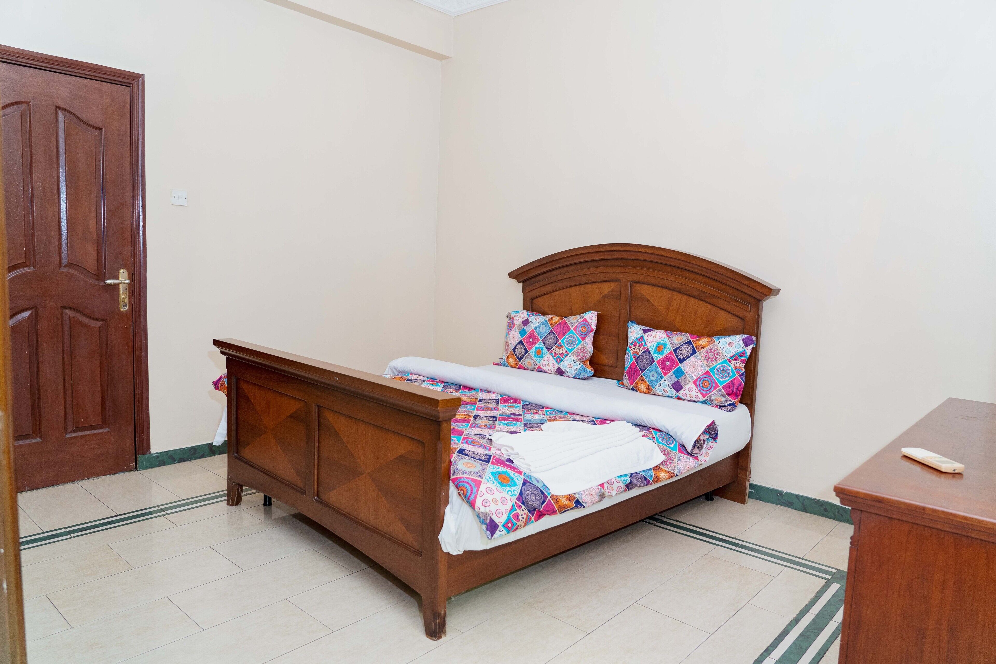 Quarto com cama de madeira, mesa de cabeceira e uma porta.