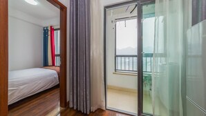Quarto com cama, porta de vidro deslizante para uma varanda e piso de madeira.