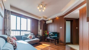 Sala de estar moderna com sofá, televisão e piso de madeira.