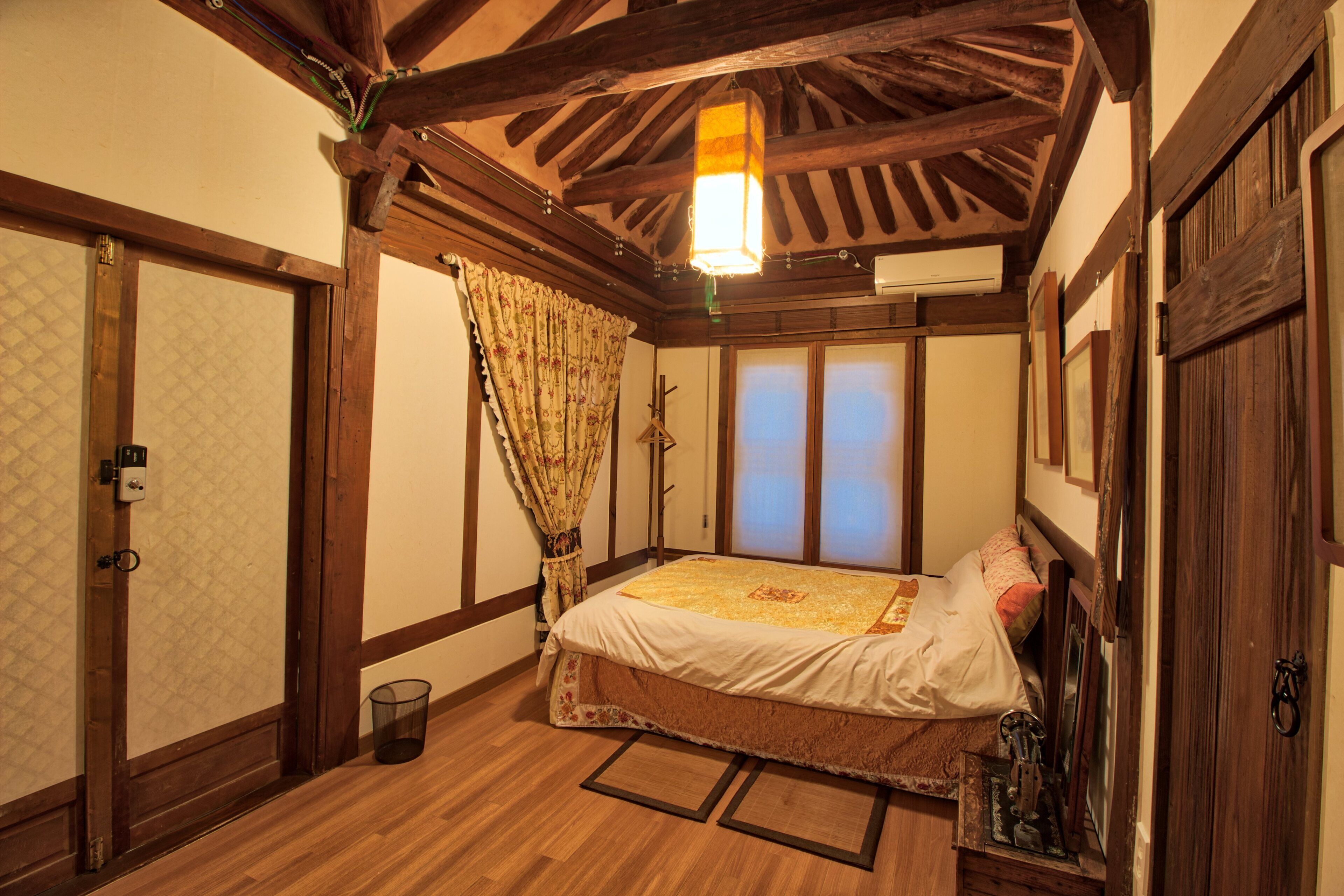 Quarto tradicional japonês com tatames, cama de madeira baixa, portas deslizantes e um pendente.
