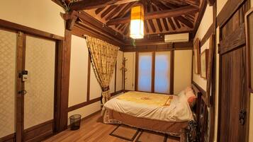 Quarto tradicional japonês com tatames, cama de madeira baixa, portas deslizantes e um pendente.