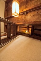 Interior em madeira com luminária pendente, corrimão de metal e banco de madeira.