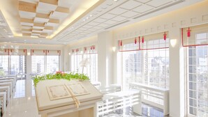 Quarto de hotel com uma grande janela, uma mesa de recepção e vista para a cidade.