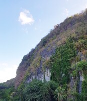 Paisagem montanhosa com vegetação densa e céu claro.