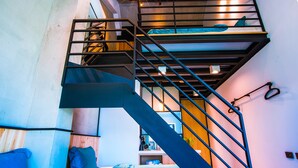 Interior com vários níveis, incluindo uma escada, beliches e uma estante com diversos objetos.