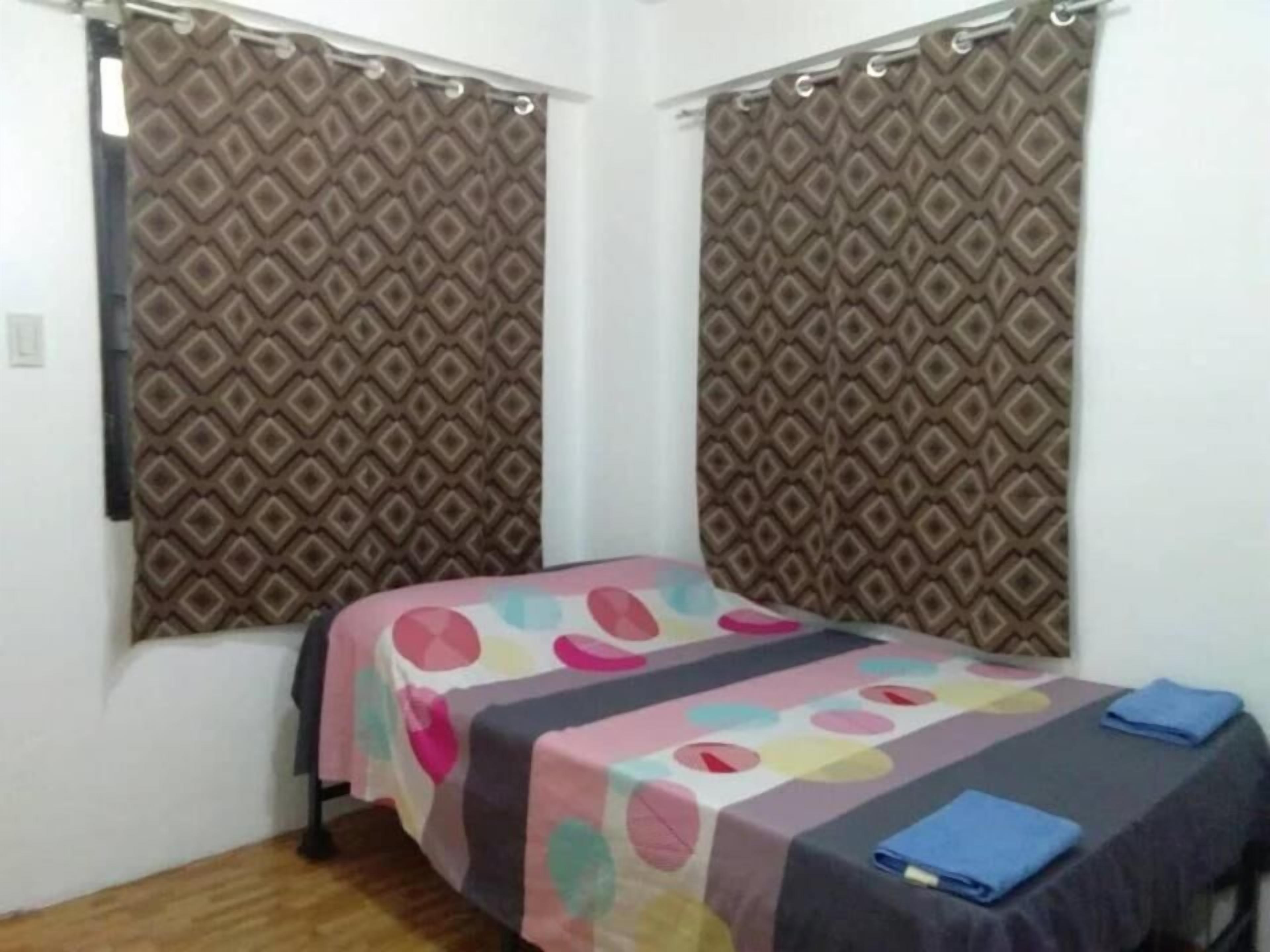 Um quarto pequeno com uma cama, uma mesa e cortinas.