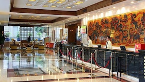 Um hall de hotel com balcão de recepção, um grande mural e um design moderno no teto.
