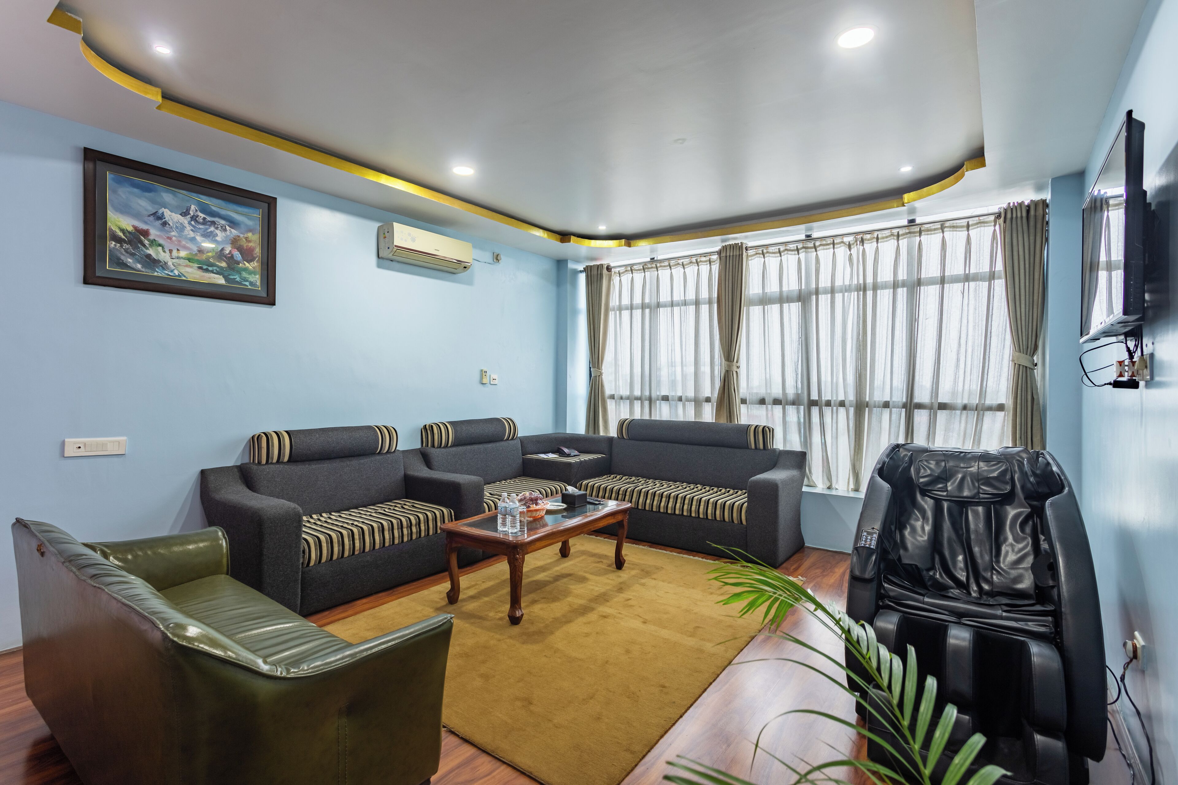 Uma sala de estar com um sofá, uma poltrona de massagem, uma mesa de centro e um quadro na parede.