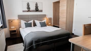 Quarto moderno com cama, mesas de cabeceira, guarda-roupa de madeira e uma pequena mesa.