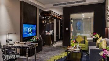 Um hall de hotel moderno com televisão de tela plana, balcão de recepção, sofá verde e mesa de centro.