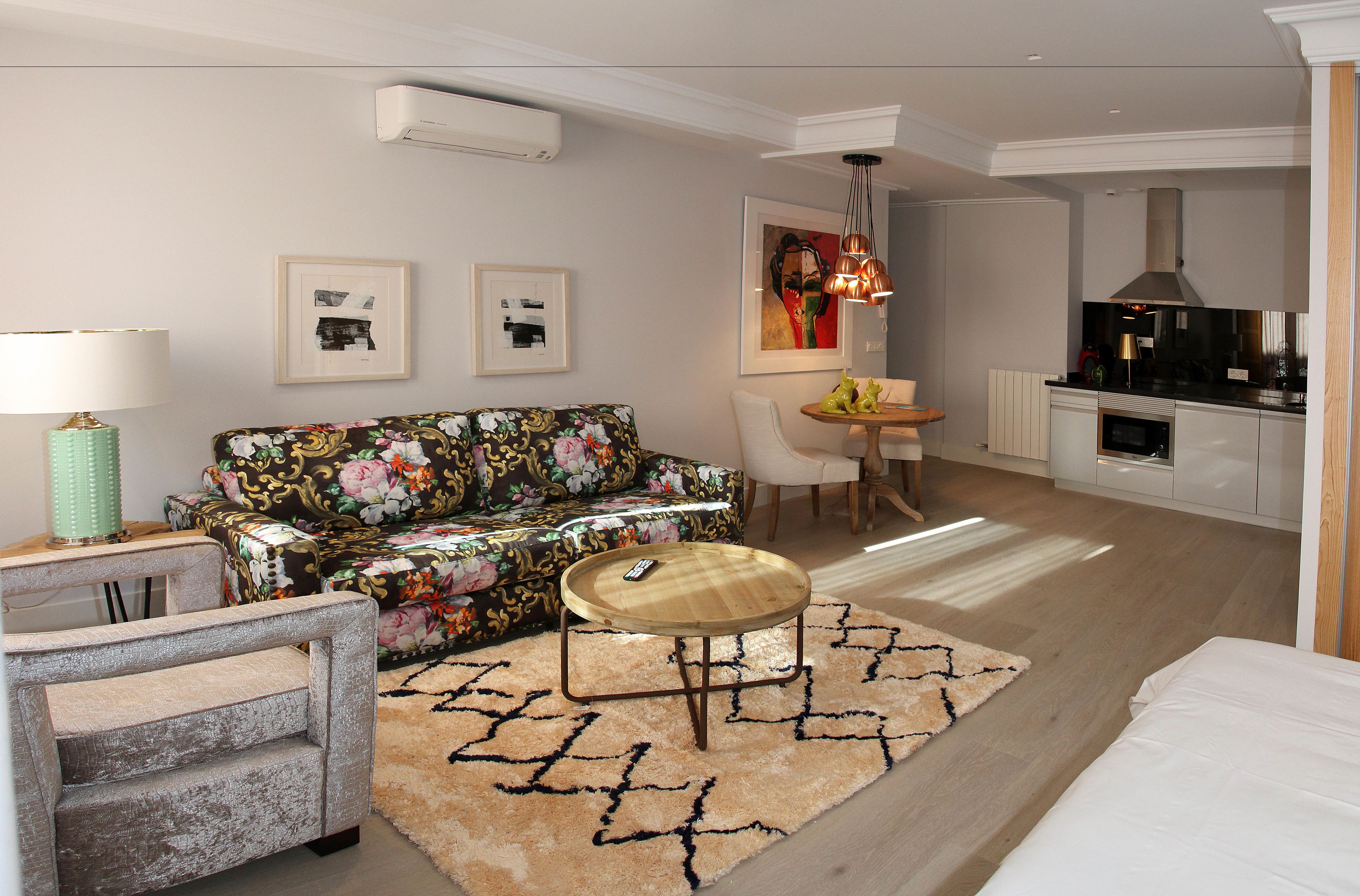 Uma sala de estar moderna com um sofá, uma mesa de centro redonda, um abajur e um tapete.