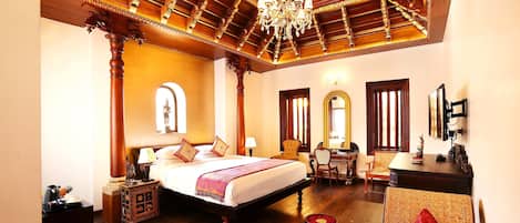 Quarto espaçoso com uma cama grande, um candelabro e teto de madeira.