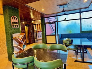 Interior de restaurante com parede verde, teto de madeira e uma grande janela.