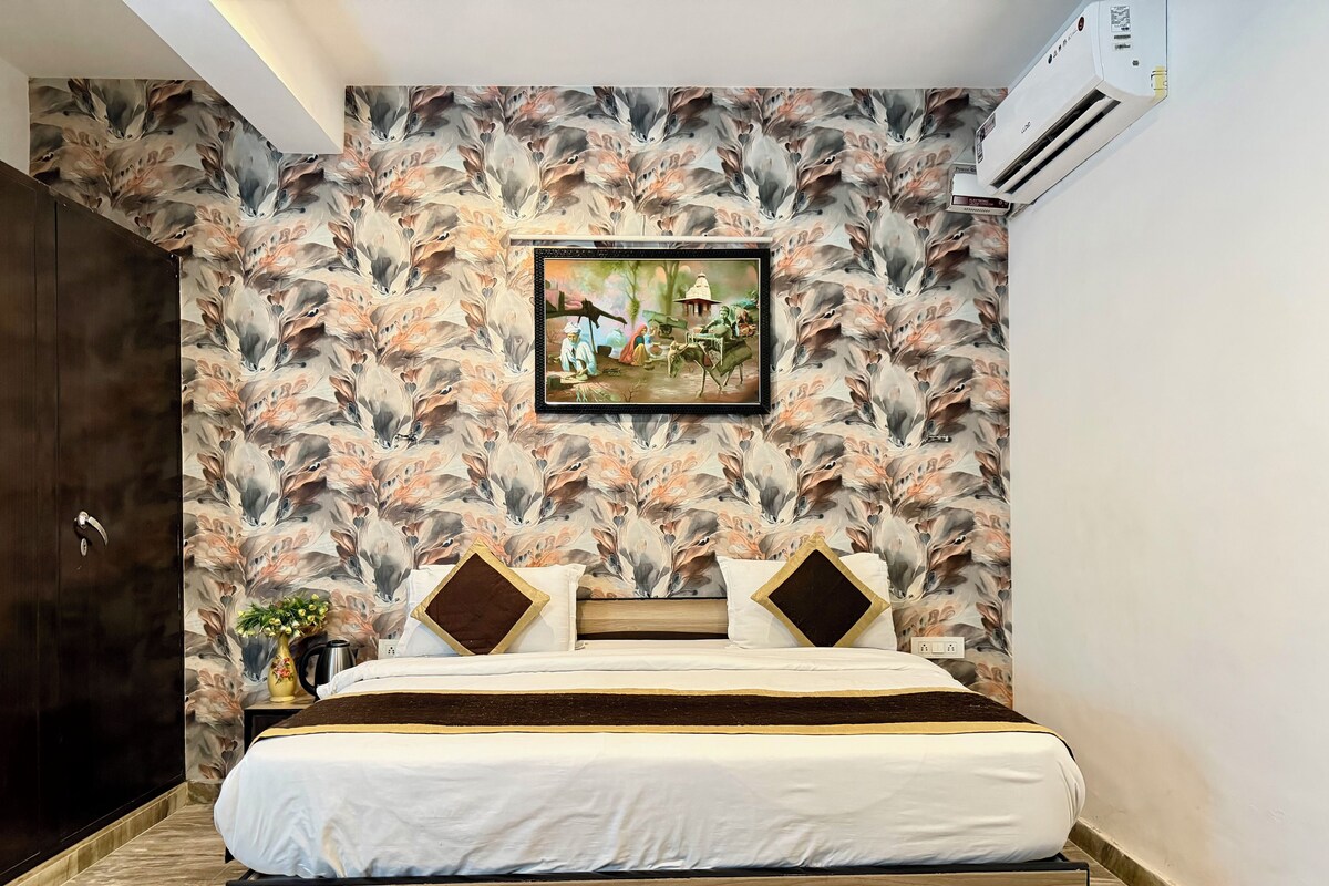 Quarto de hotel com cama, quadro na parede e uma porta.