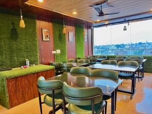 Um restaurante com parede verde, painéis de madeira e vista para a paisagem urbana.