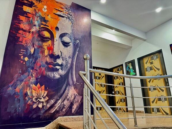 Escada com corrimão de metal que leva a um quarto com uma grande pintura abstrata.
