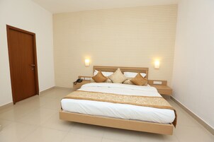 Quarto bem arrumado com cama de madeira, paredes bege e duas luminárias de cabeceira.