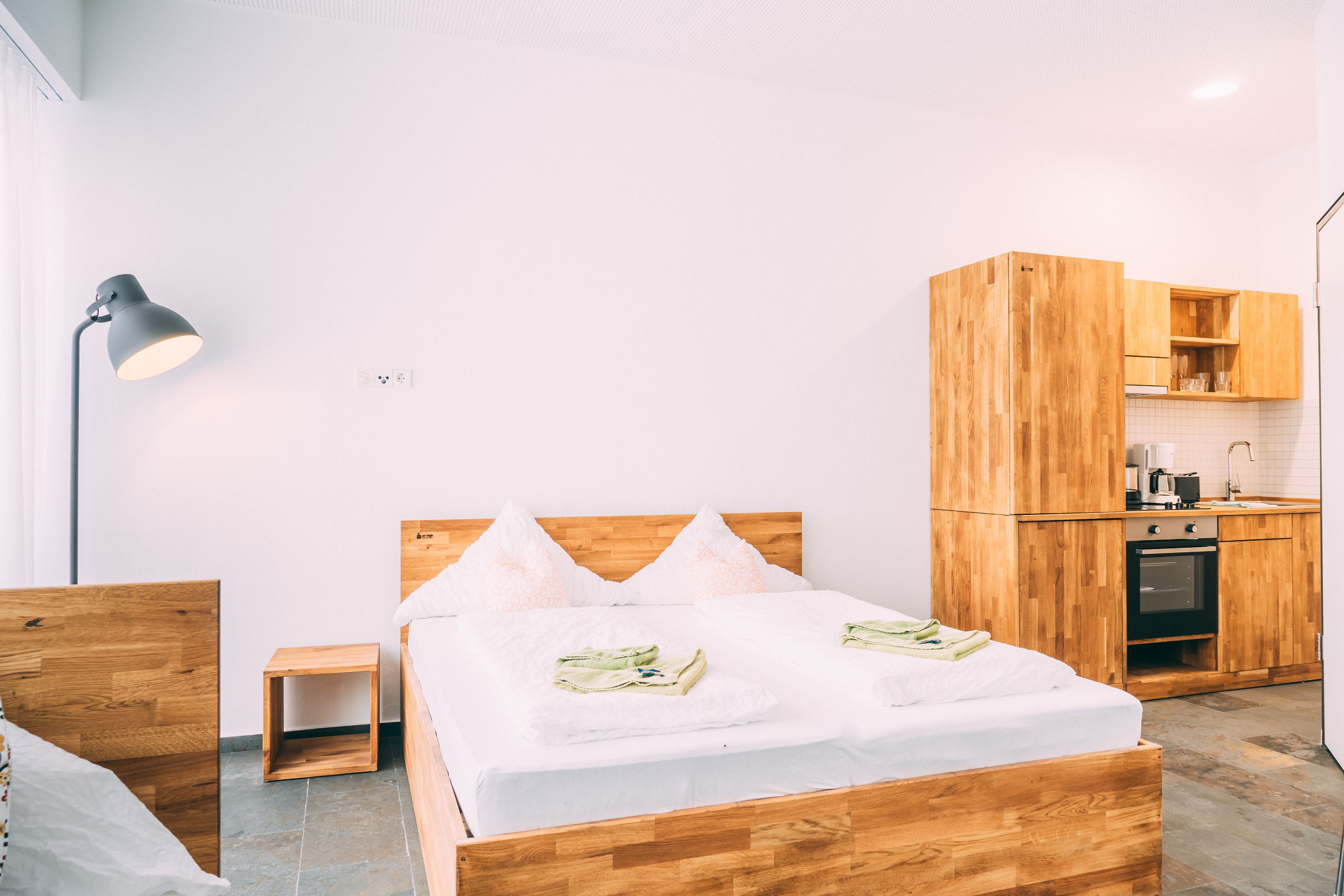 Um quarto moderno com cama de madeira, mesa de cabeceira e criado-mudo de madeira.