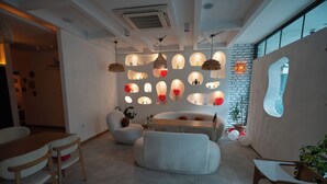 Decoração moderna com área de refeições, sofás e uma parede com objetos vermelhos e brancos iluminados.