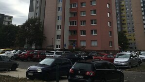 Um edifício residencial de vários andares com um estacionamento na frente.