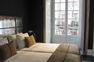 Quarto com duas camas, uma janela grande e vista para a rua.