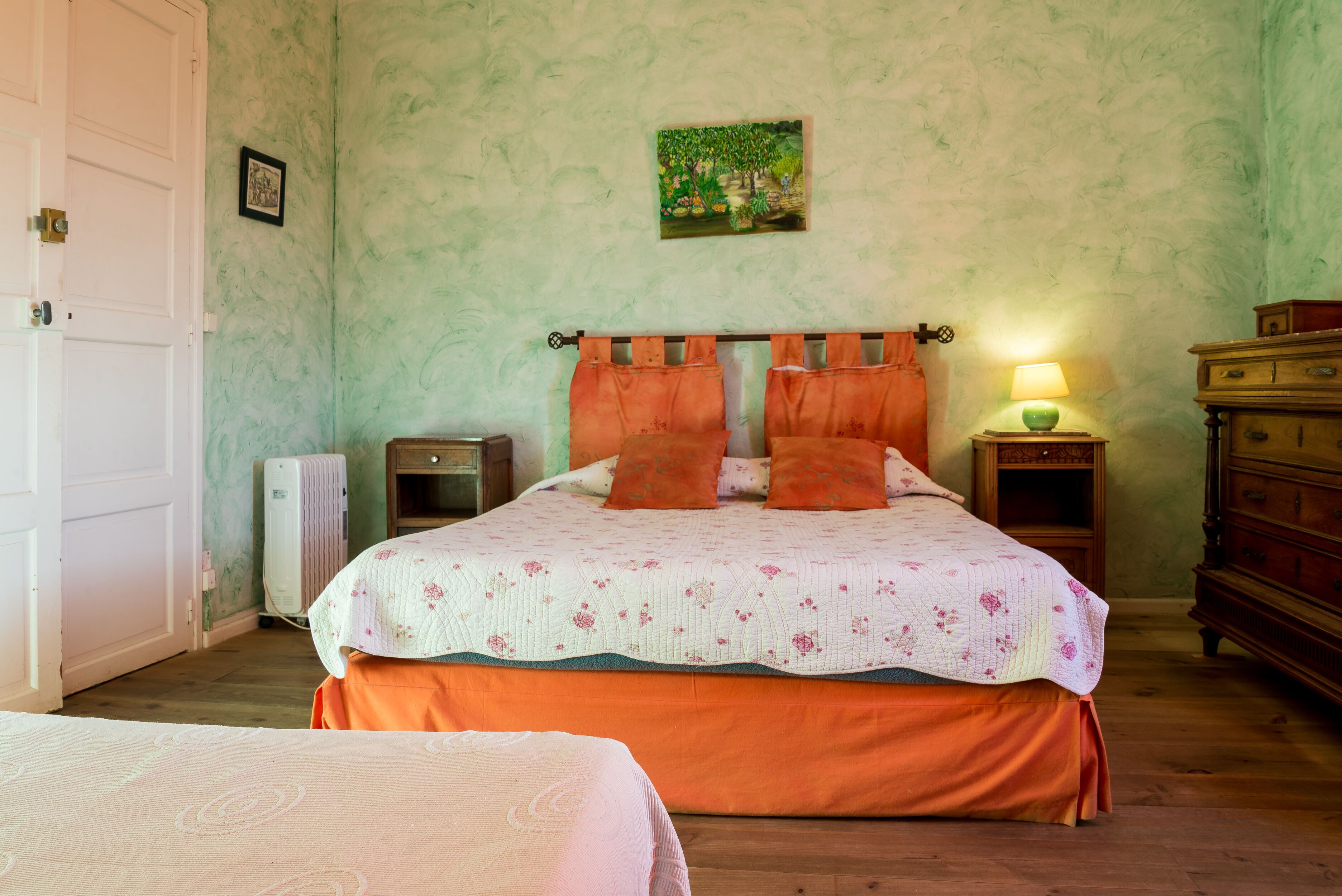 Quarto com cama, mesa de cabeceira, cômoda e um quadro na parede.
