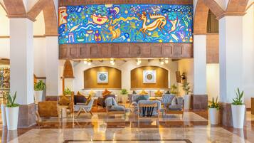Um hall com um grande mural colorido, áreas de estar e plantas em vasos.