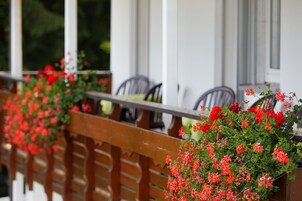 Guarda de varanda de madeira com flores vermelhas.