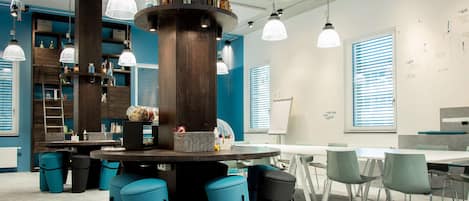 Uma sala de reuniões moderna com uma mesa central, cadeiras azuis e iluminação pendente.