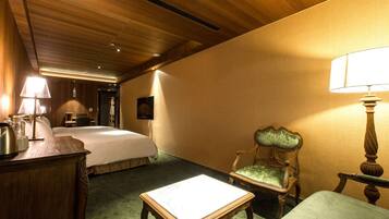 Quarto de hotel com uma cama, uma cadeira, uma mesa e um abajur.