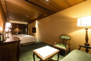 Quarto de hotel com uma cama, uma cadeira, uma mesa e um abajur.