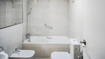 Uma casa de banho moderna com banheira, duas pias e sanita.