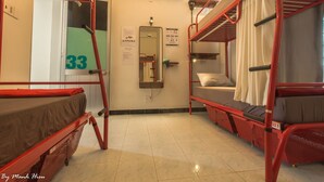 Quarto de dormitório com beliches, um espelho, porta-toalhas e o número 33 na parede.