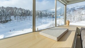 Interior moderno com grandes janelas que oferecem vista para uma montanha nevada.