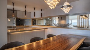 Cozinha moderna com ilha central, iluminação pendente e vista da cidade.