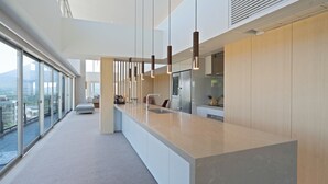 Cozinha moderna com uma ilha grande, iluminação pendente e vista para a cidade.