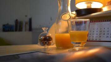 Uma mesa com um copo de sumo de laranja, um copo de água, uma garrafa de sumo de laranja e um pequeno frasco com frutos secos.
