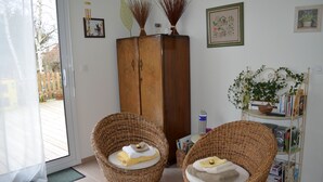 Um quarto com duas cadeiras de vime, um armário de madeira e uma estante de livros com livros e uma planta.
