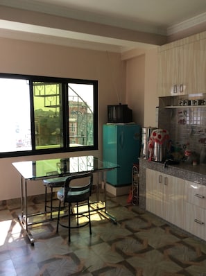 Uma cozinha com mesa de vidro, geladeira verde-água e armários.