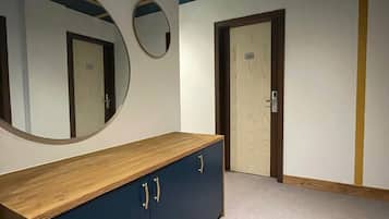 Quarto com um armário de madeira, um espelho e duas portas.