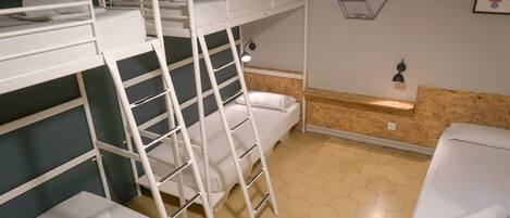 Quarto com beliche, uma pequena estante e uma casa de banho.