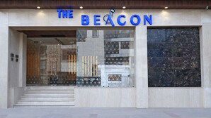 Exterior do hotel The Beacon, com fachada moderna, amplas janelas de vidro e entrada destacada.