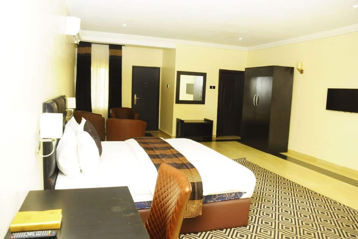 Quarto de hotel com cama, escrivaninha, cadeira, guarda-roupa e espelho.