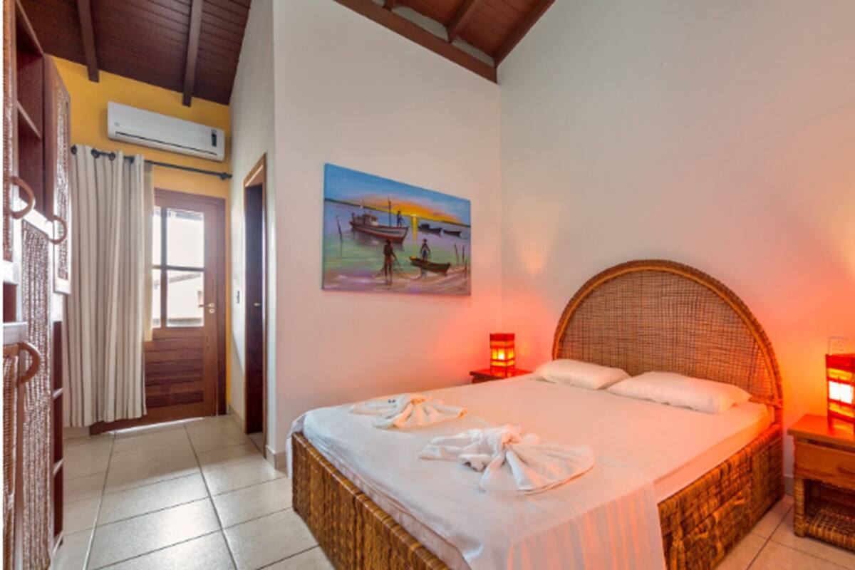 Um quarto com uma cama grande, um quadro na parede e duas luminárias de cabeceira.