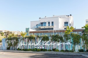 Um edifício moderno com um cercado colorido e vegetação na frente.