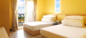 Quarto de hotel com duas camas, varanda e vista para área verde.