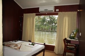 Um quarto com uma cama, uma janela com cortinas, uma cadeira e um aparelho de ar condicionado.