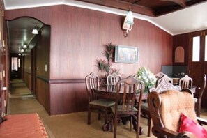 Uma sala de jantar com uma mesa e cadeiras de madeira, um candelabro e um quadro na parede.