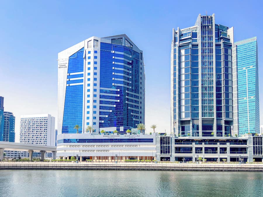 Um edifício moderno com fachada azul marcante, grande entrada de vidro e vista para o cais.